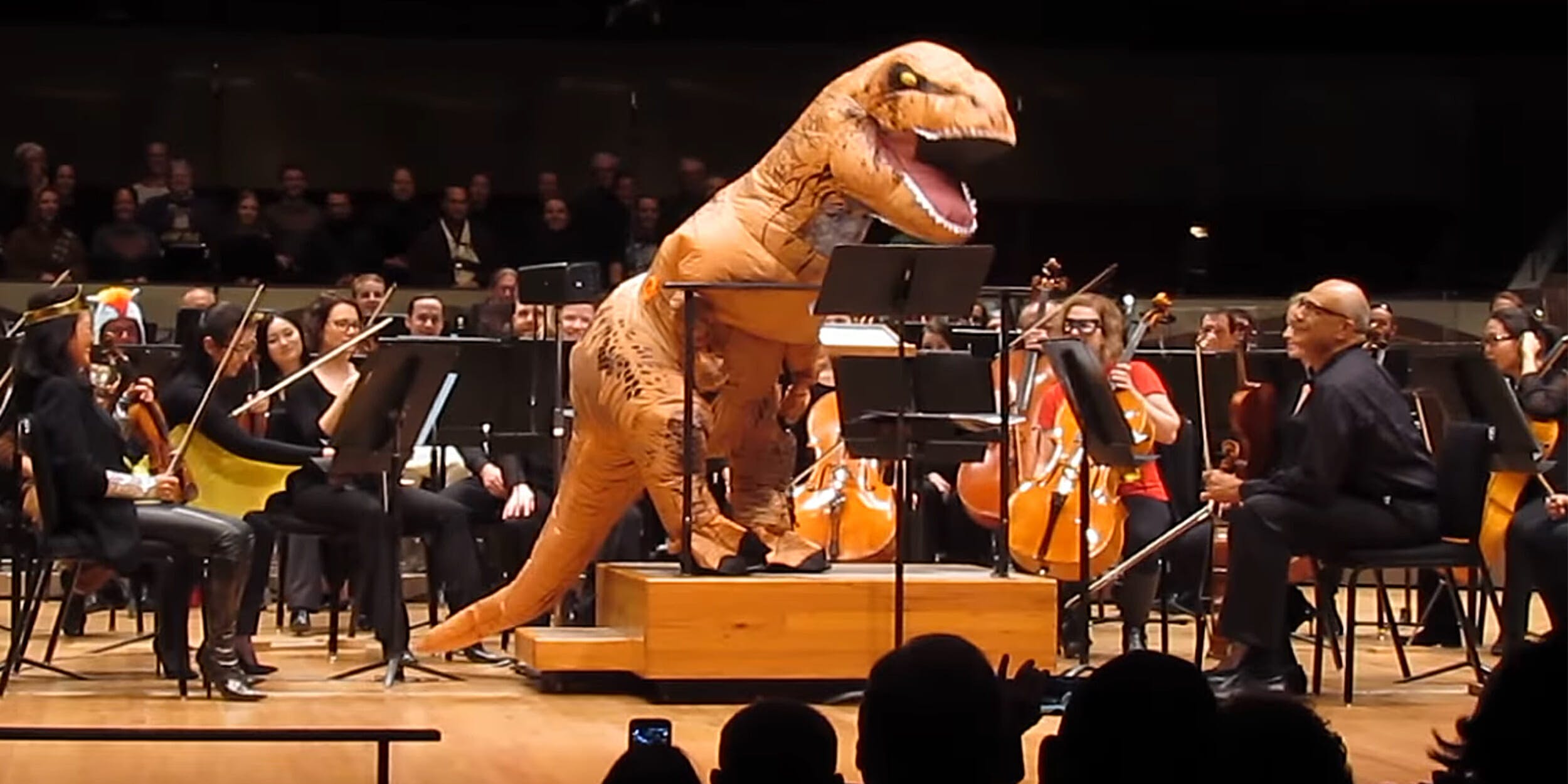 Conductor leads full orchestra in ‘Jurassic Park’ theme – dressed as a tiny-armed T-Rex ...